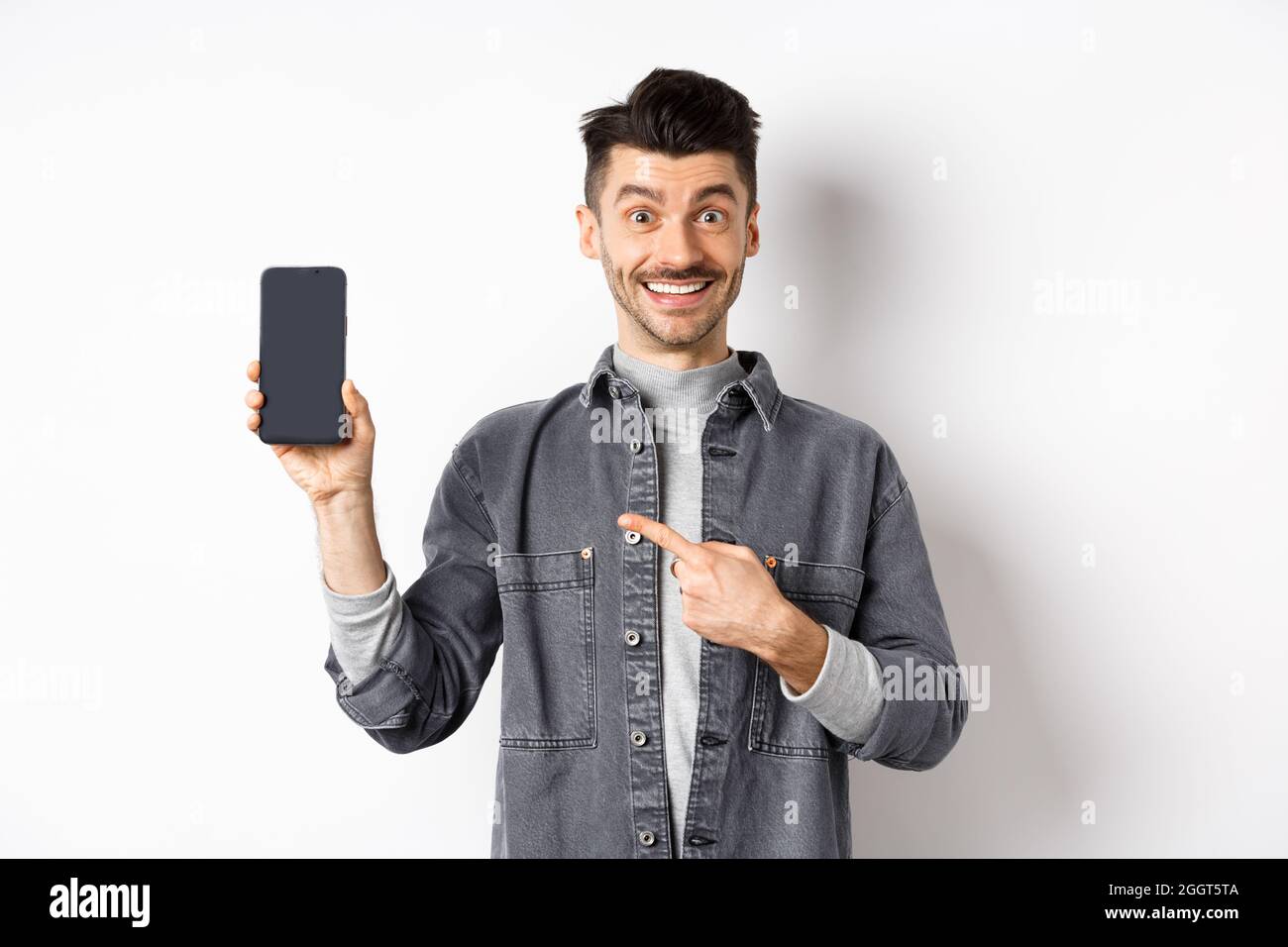 Handsome smiling man pointing finger at smartphone screen, showing ...