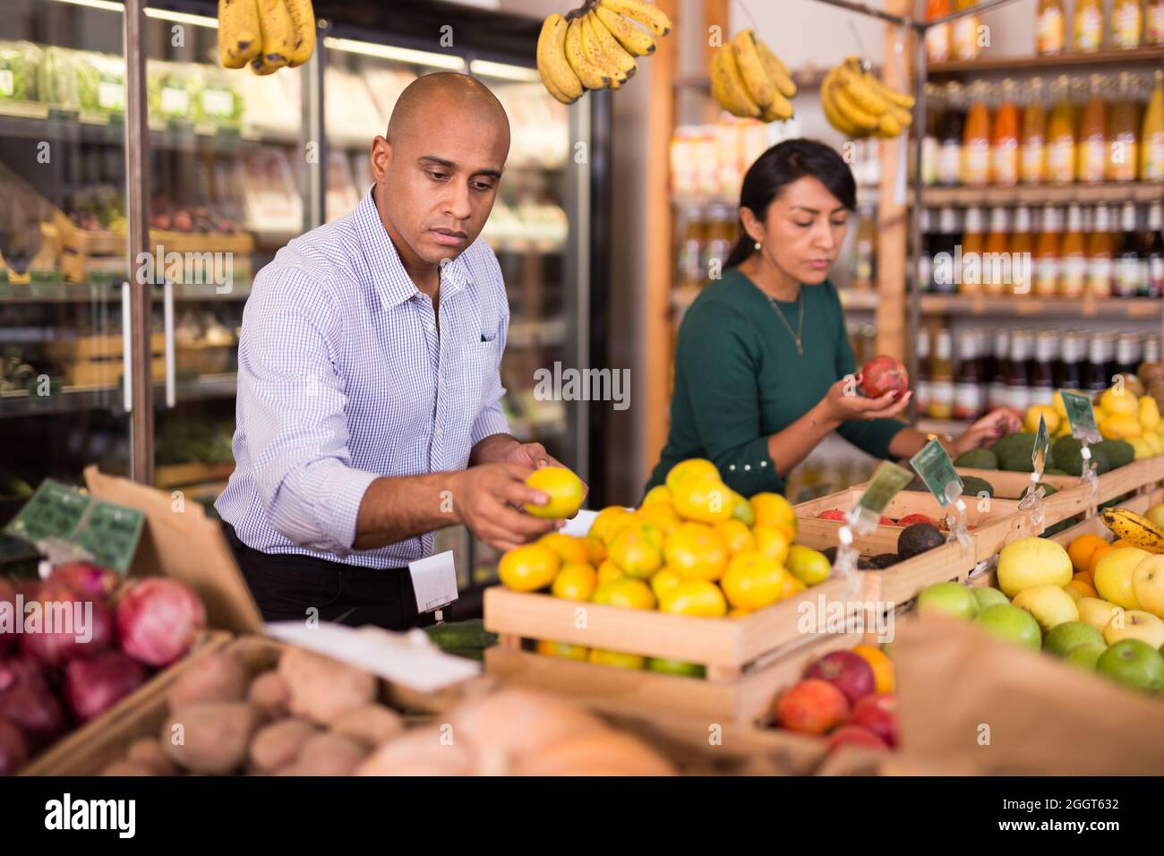 Latin american man choosing ripe mandarines in food store Stock Photo ...