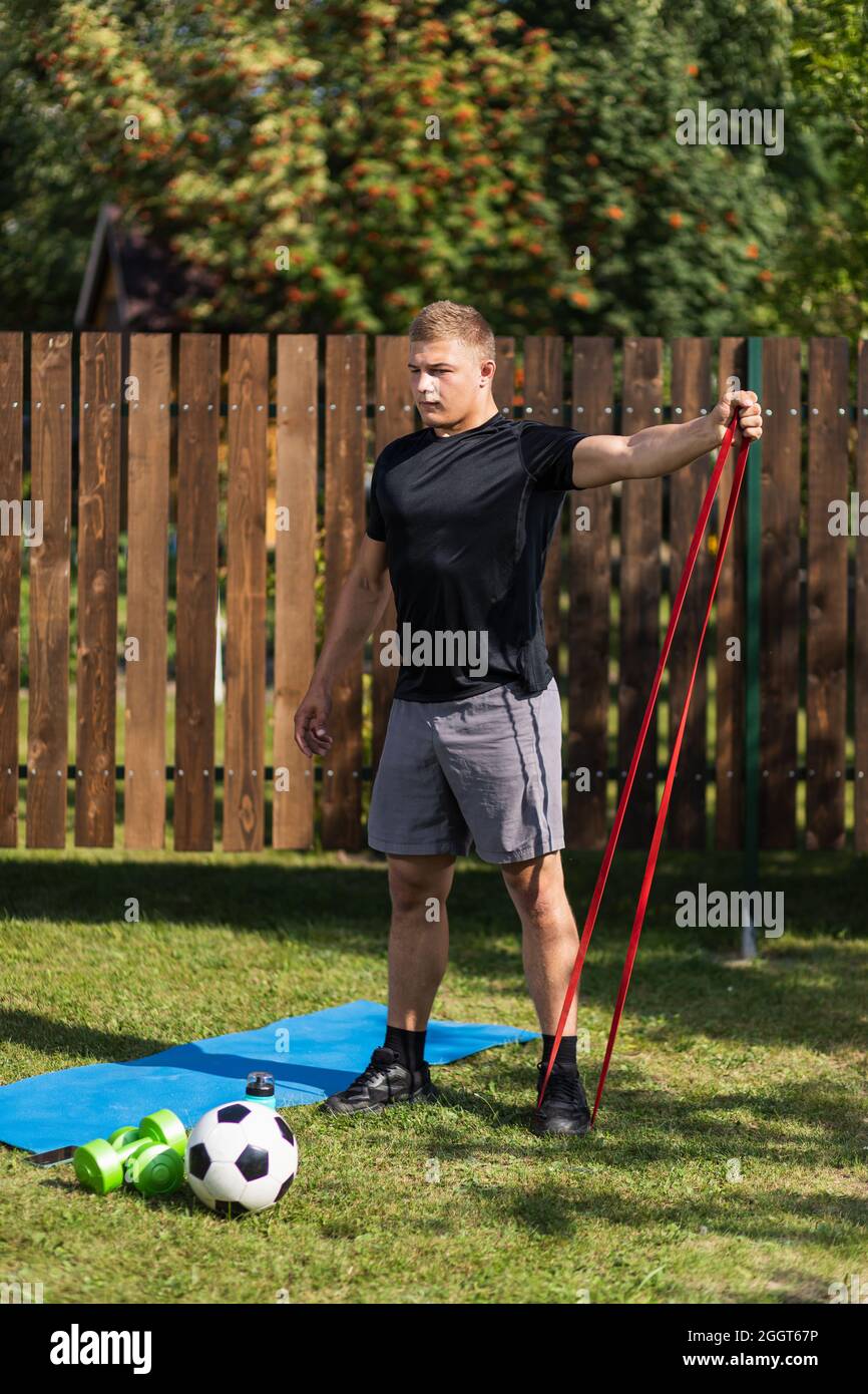 The young man goes in for sports at home in backyard in summer day ...