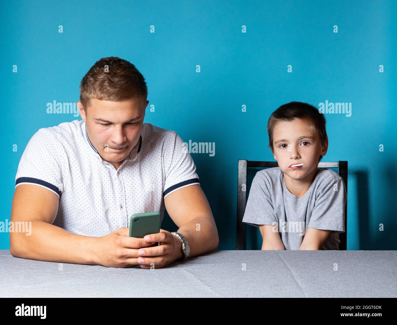 Home lessons with the child, dad is distracted by the phone while the ...