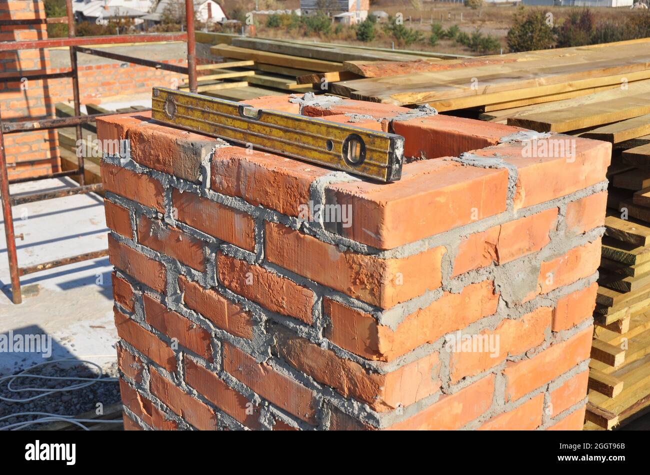 Building brick chimney in unfinished house construction roof ...