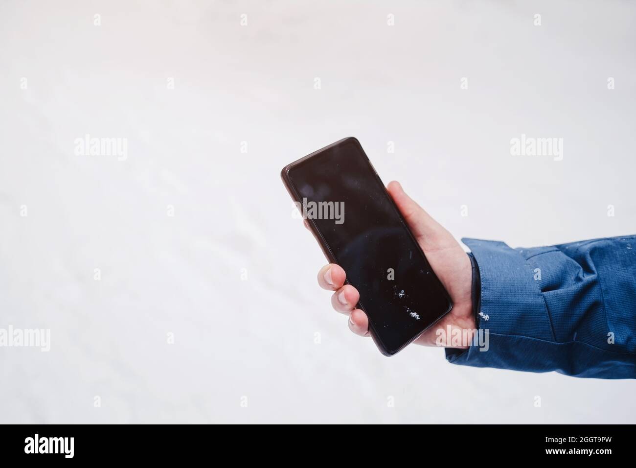 cell phone in a man's hand against a beautiful in the winter snow ...