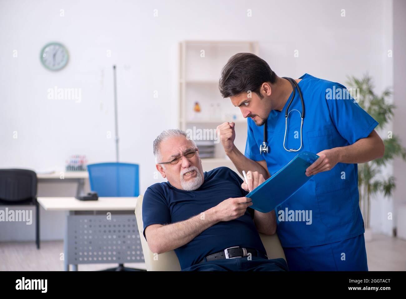 Old man visiting young doctor Stock Photo - Alamy