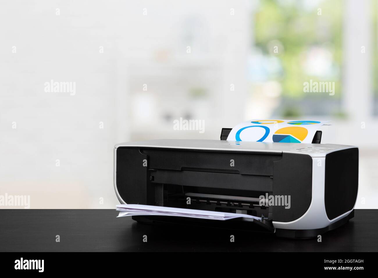 Compact laser printer on black desk against blurred background Stock ...