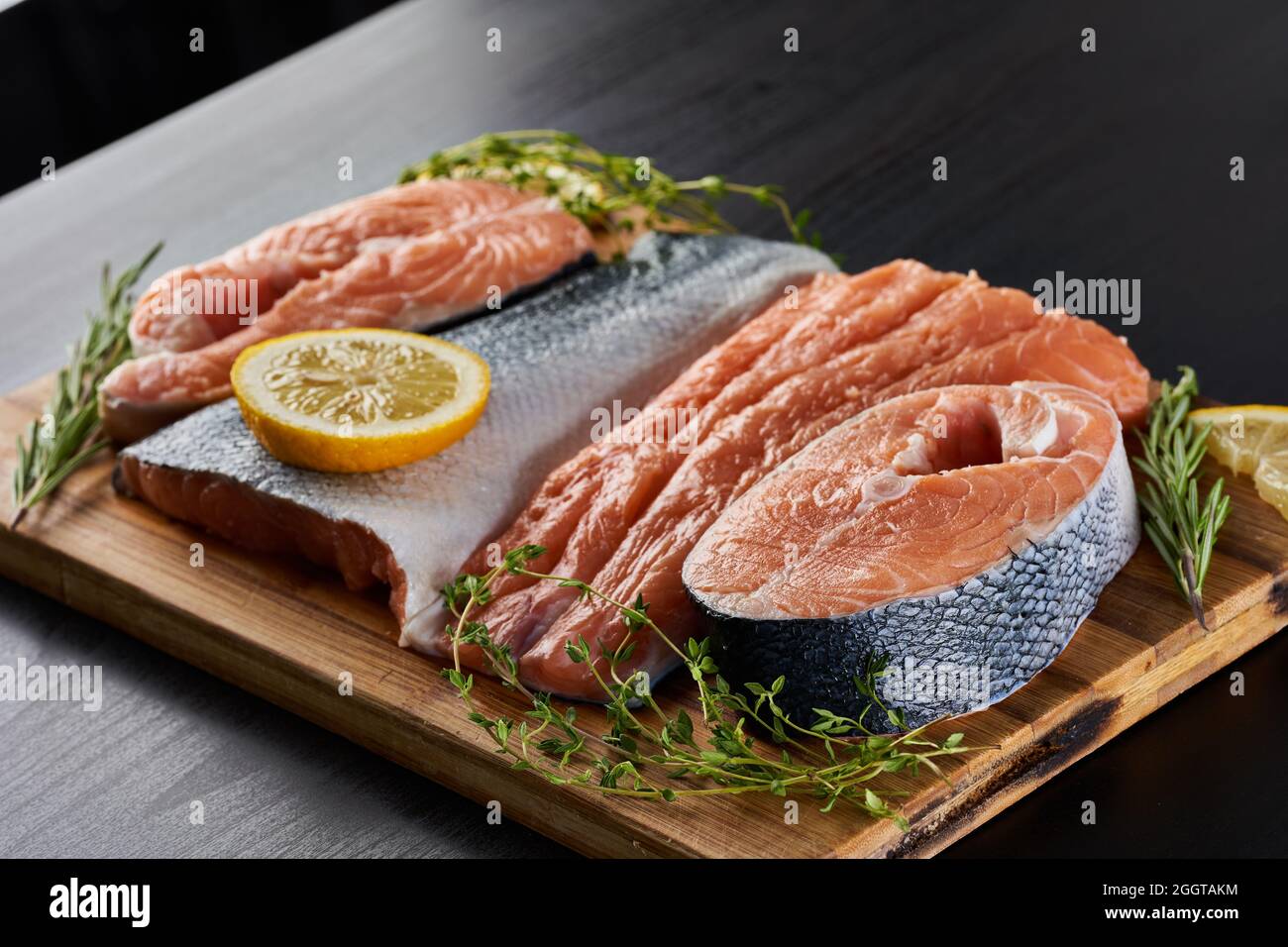 Raw salmon fillets and medallions with lemon and herbs on a wooden ...
