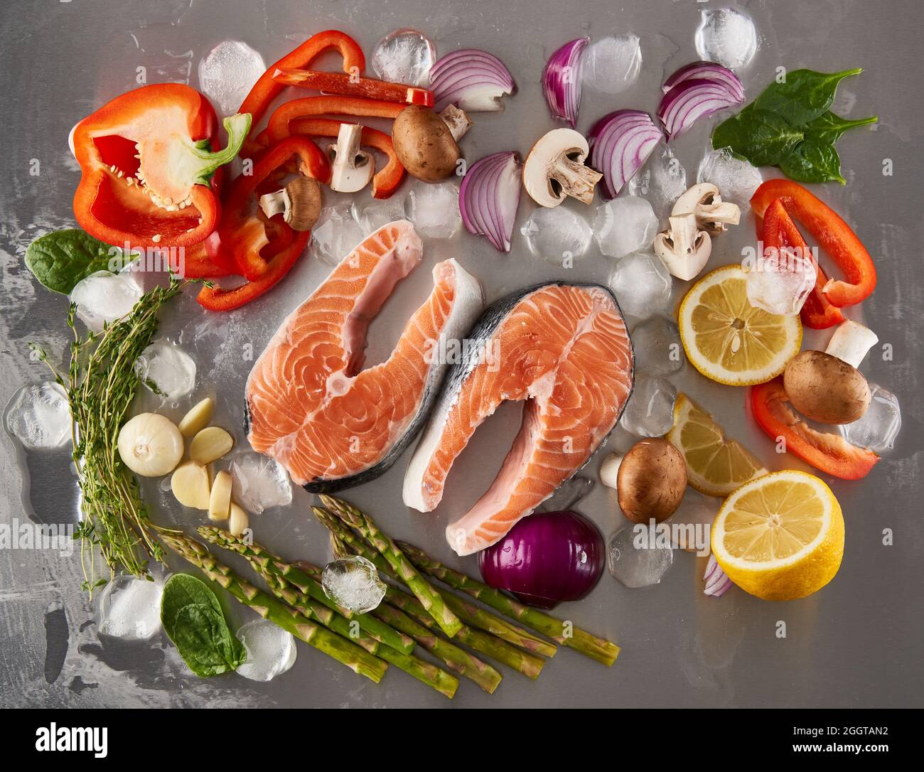 Fresh raw salmon medallions with vegetables on ice on a stainless steel ...