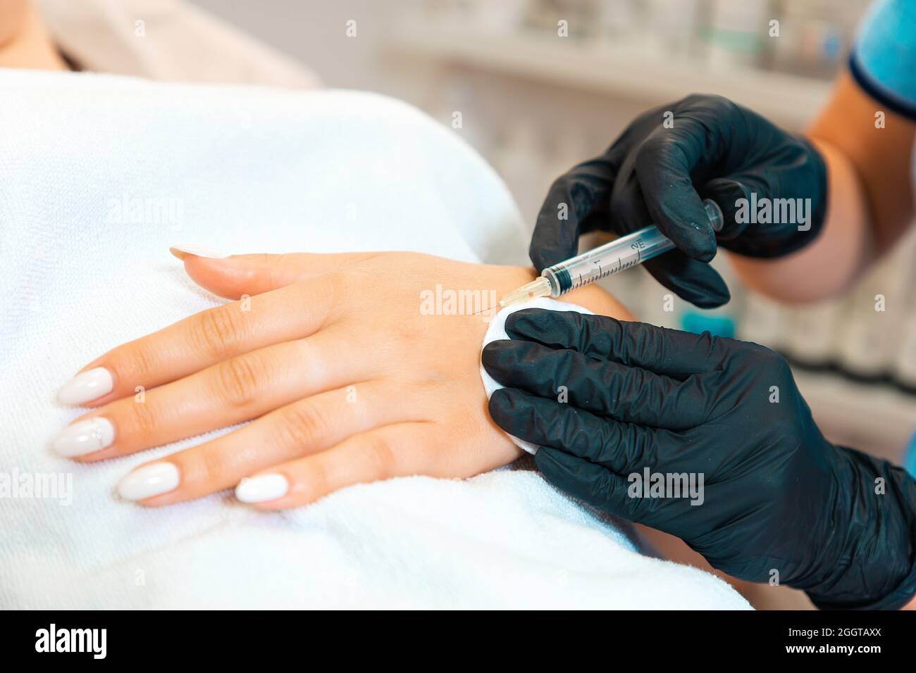 Cosmetologist makes injections of botulinum toxin on the client's hand ...