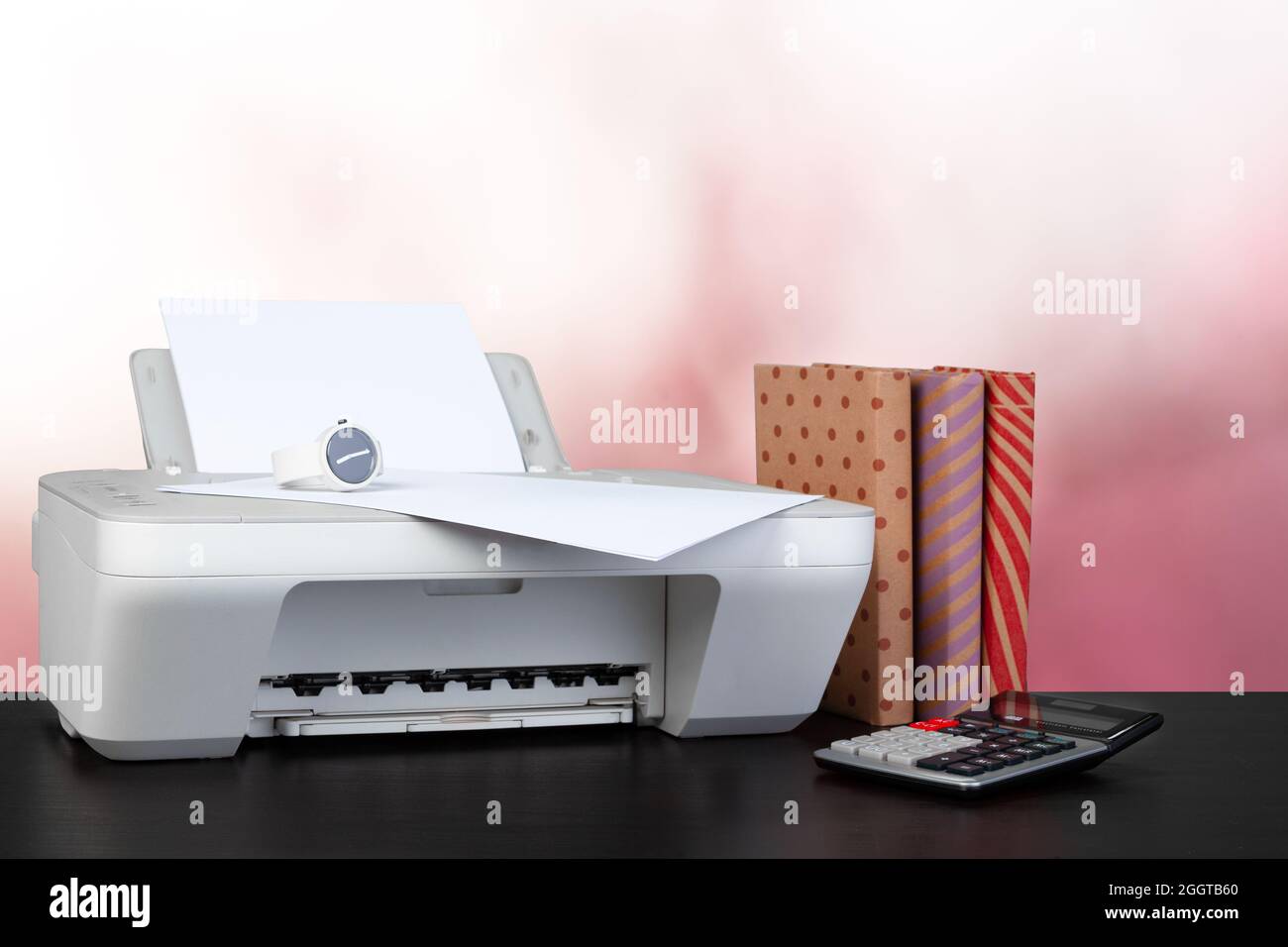 Compact home printer on desk with books against blurred background ...
