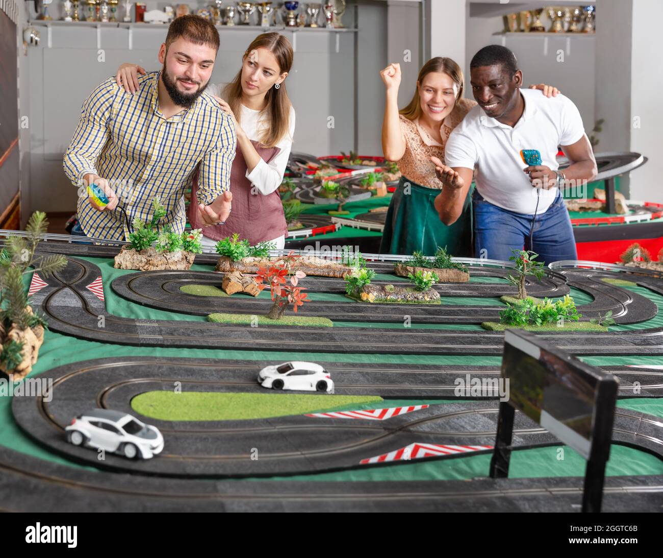 Girls with guys play slot car racing models Stock Photo - Alamy