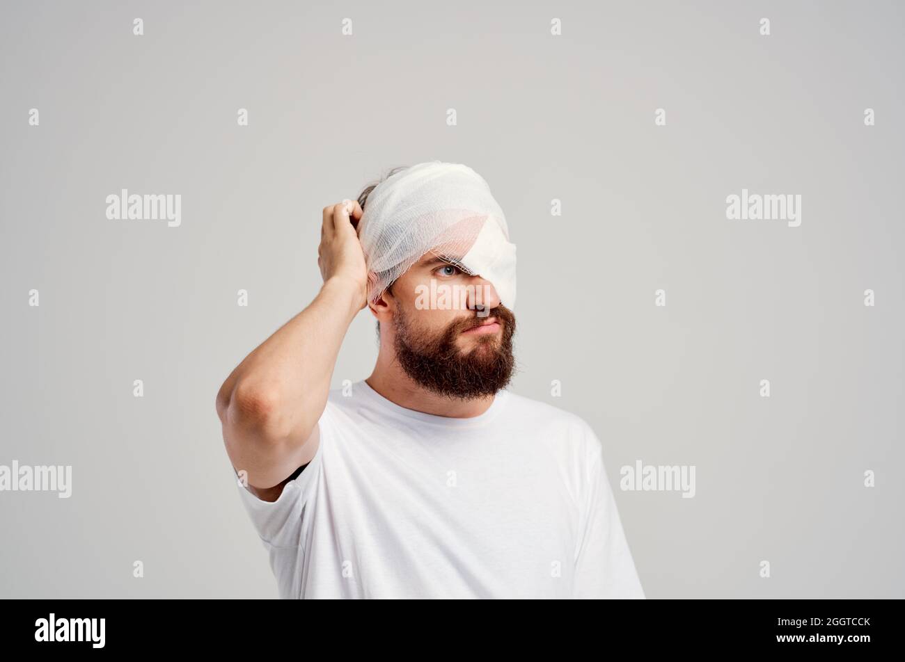 sick man with bandaged head and eye hospitalization light background ...