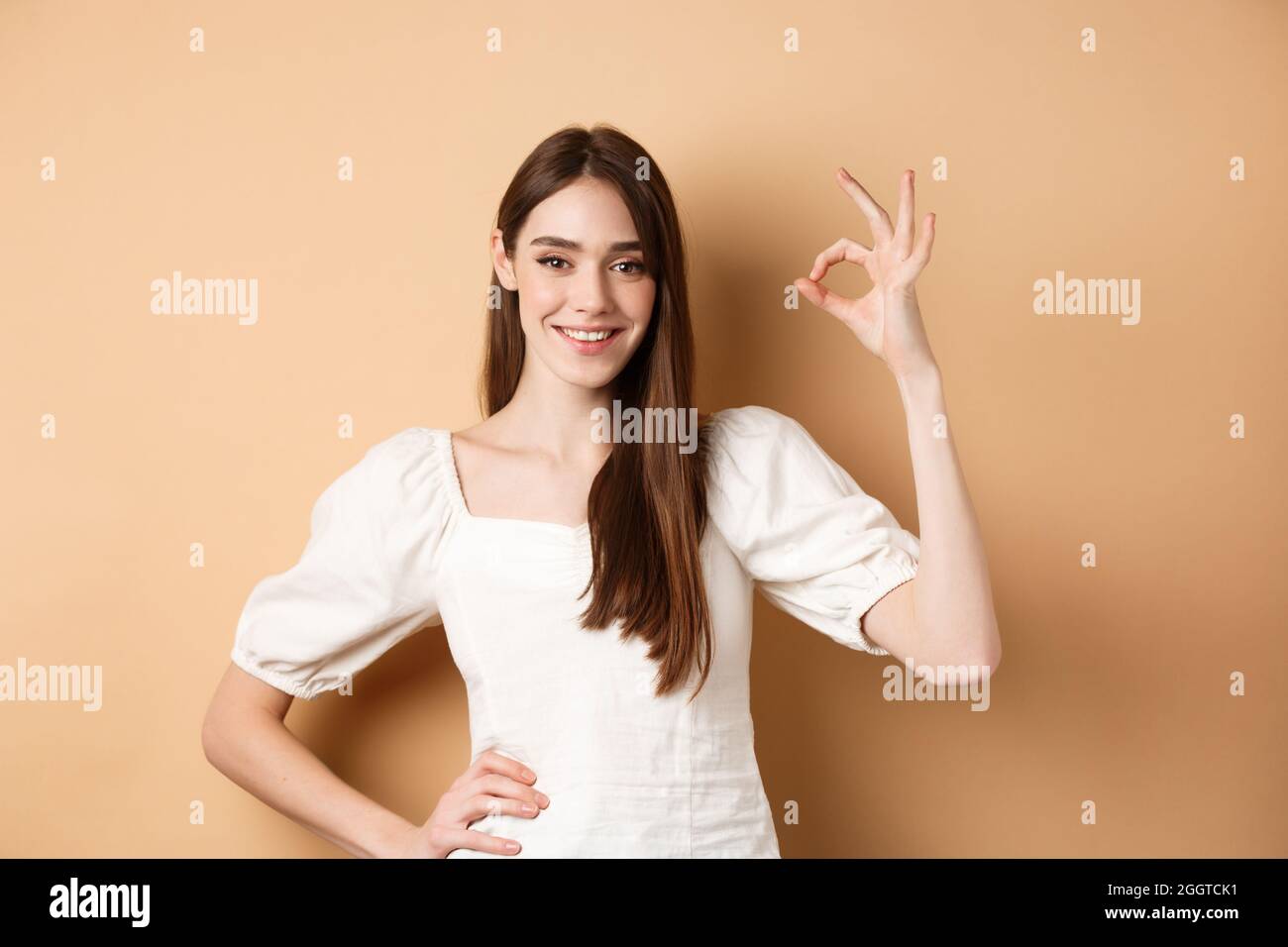 Very good. Smiling cute woman in white blouse showing okay sign in ...