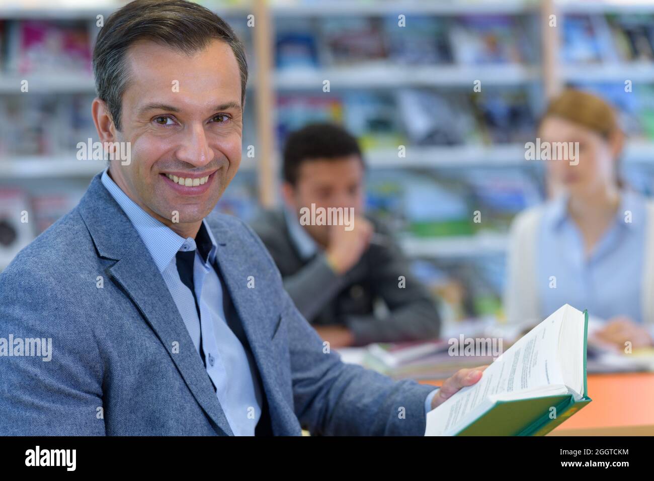 suited man holding book in library Stock Photo - Alamy