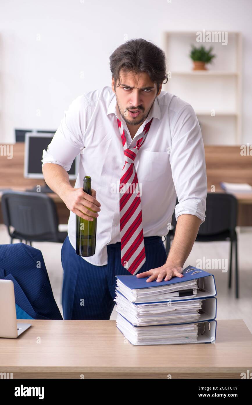 Young alcohol addicted businessman employee working in the office Stock ...