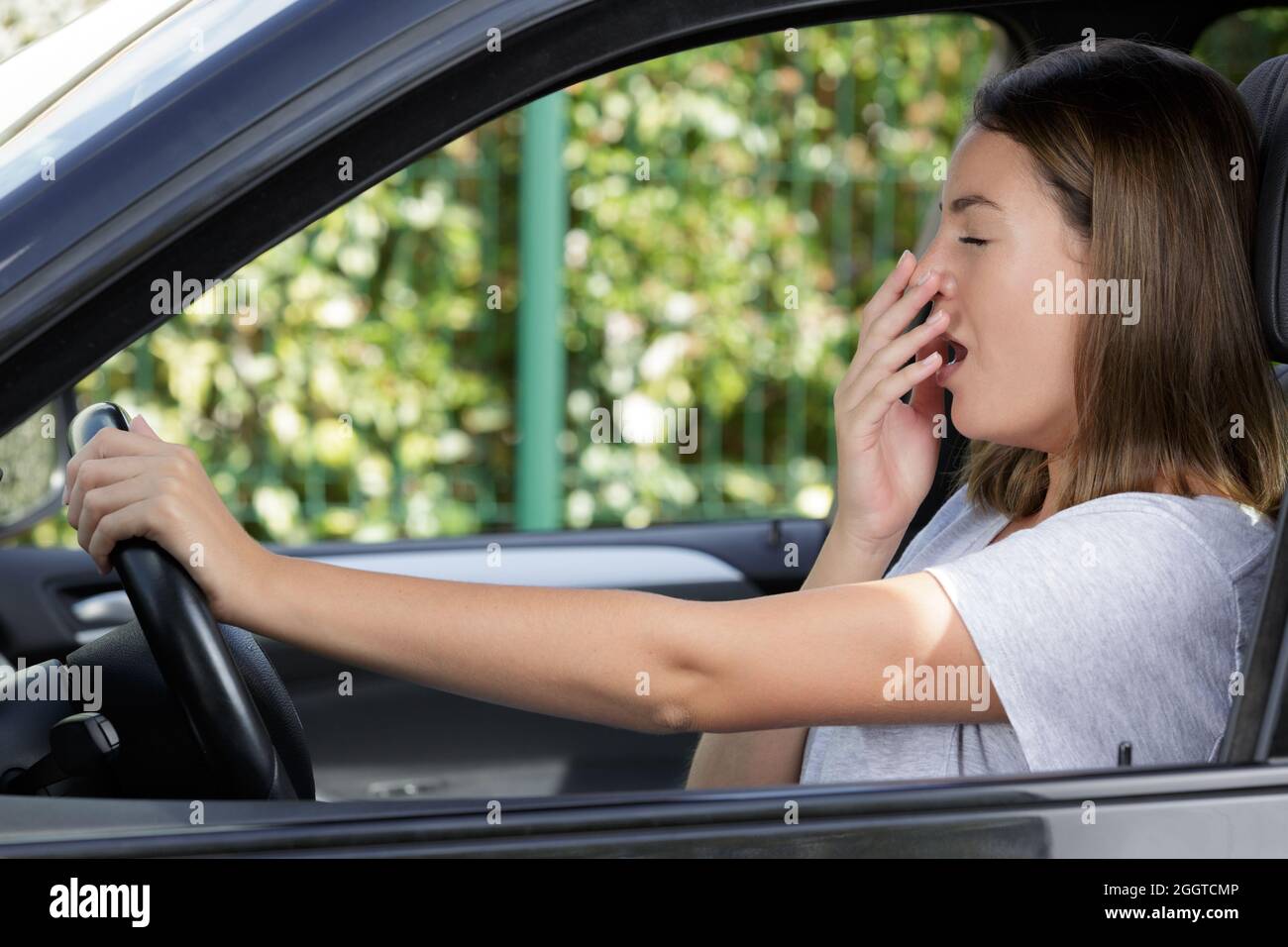 side view of a young woman yawning inside car Stock Photo - Alamy