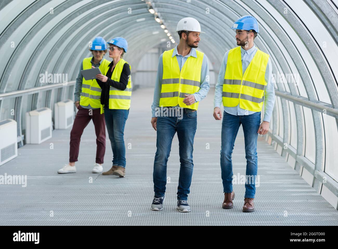 workers in high-visibility vests walking through tunnel Stock Photo - Alamy