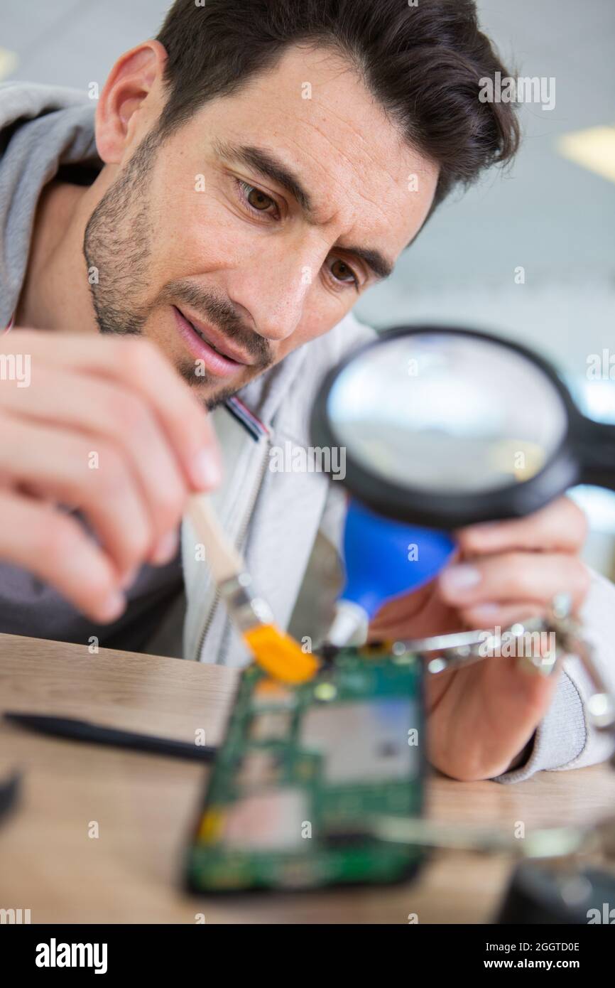 engineer examining computer circuitry though magnifier Stock Photo - Alamy