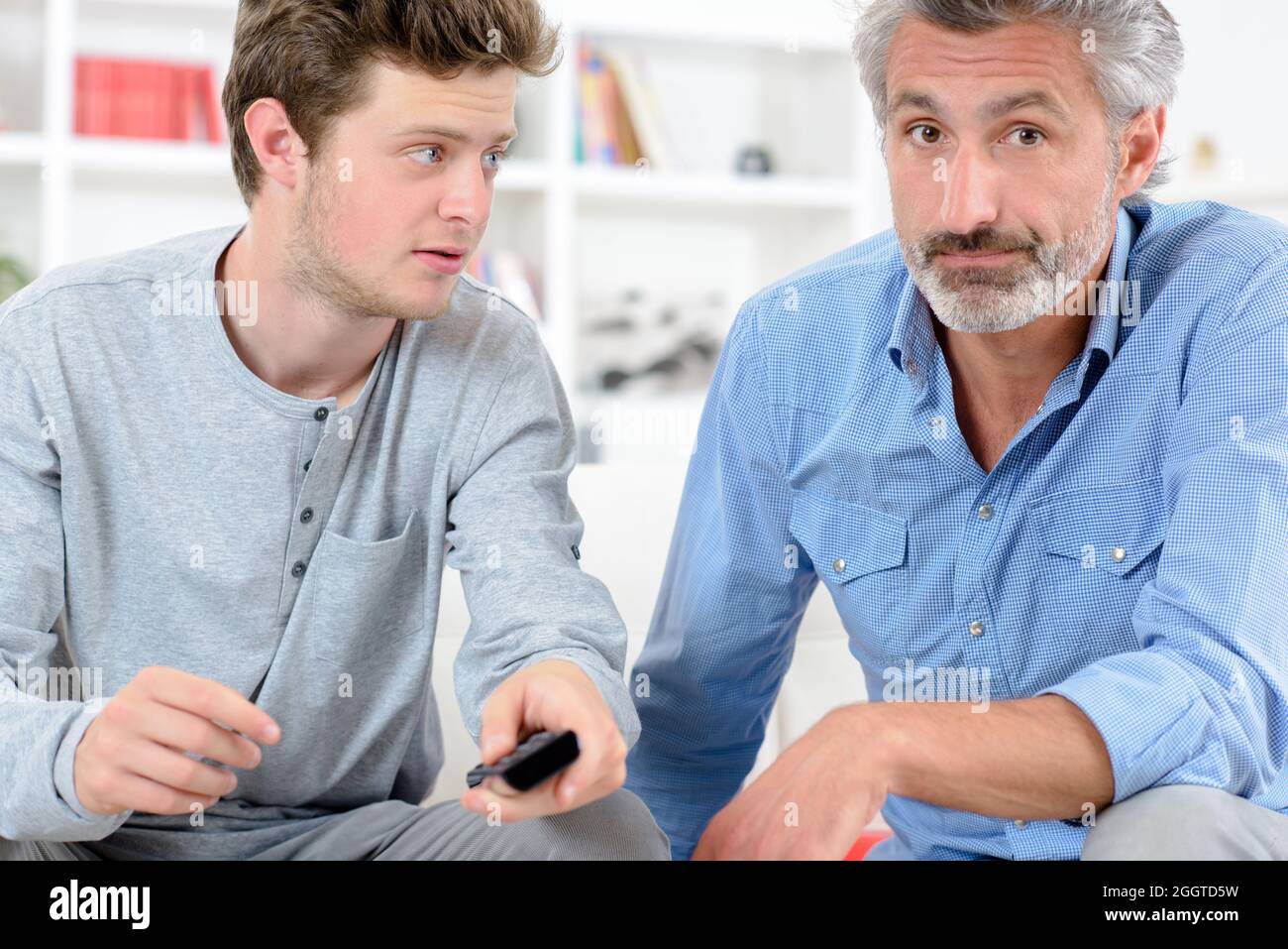 Man making knowing expression as son holds remote control Stock Photo ...