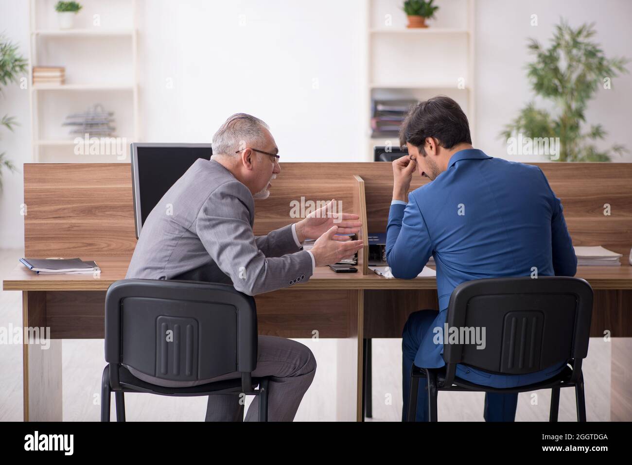 Two male employees working at workplace Stock Photo - Alamy