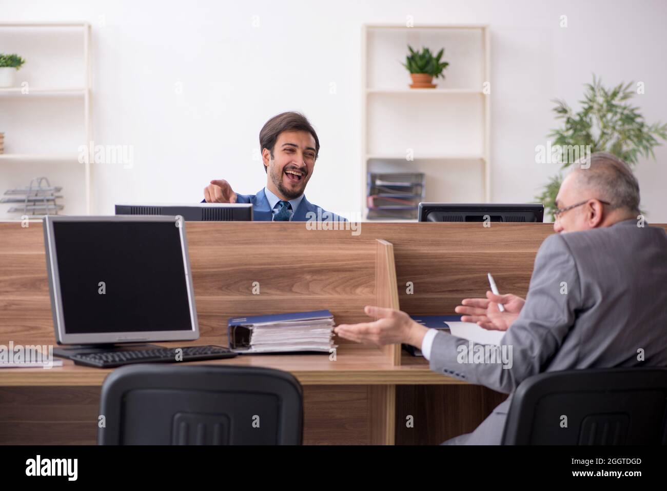 Two male employees working at workplace Stock Photo - Alamy