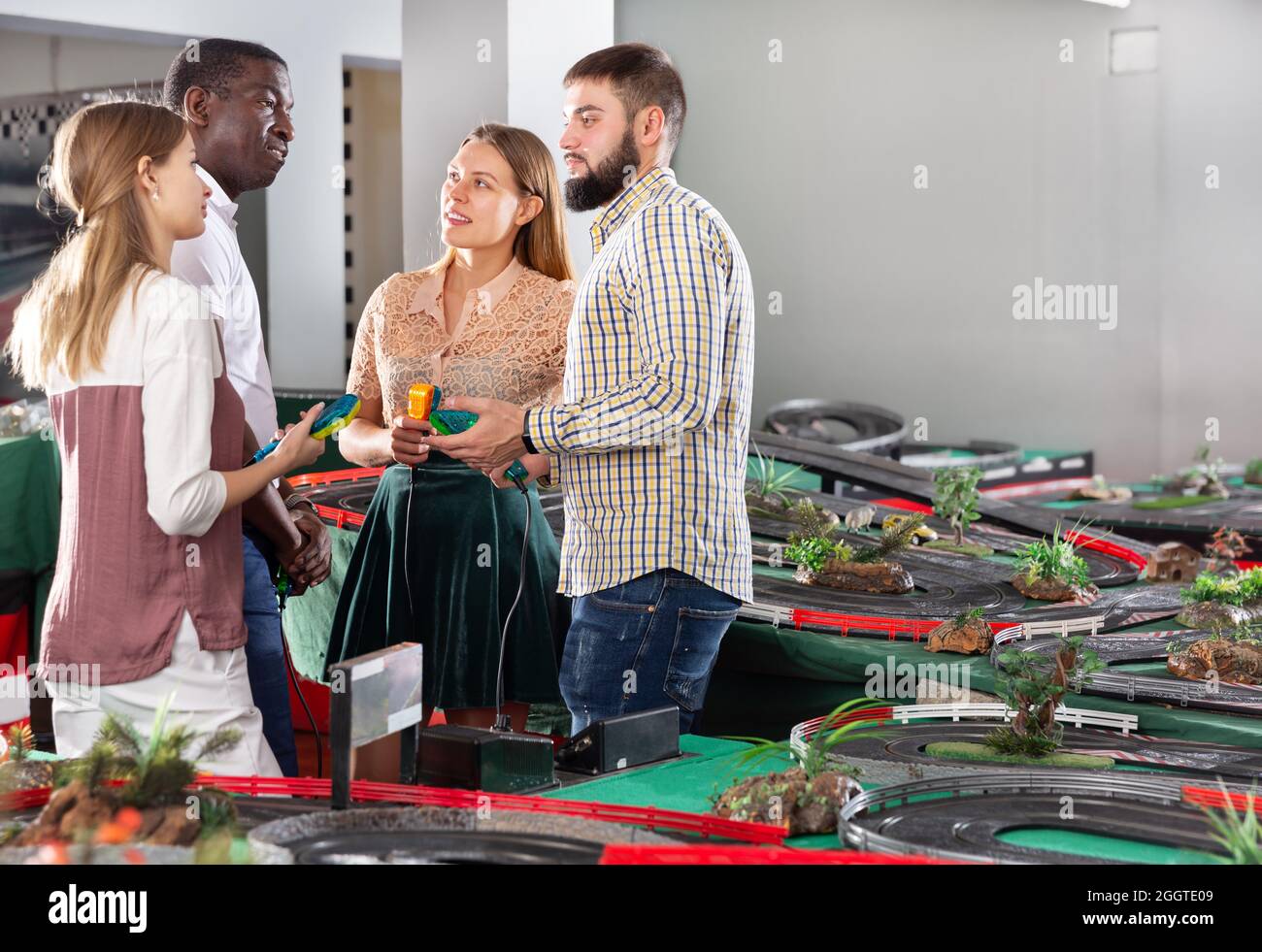 Friends discuss the game with models of race cars Stock Photo - Alamy