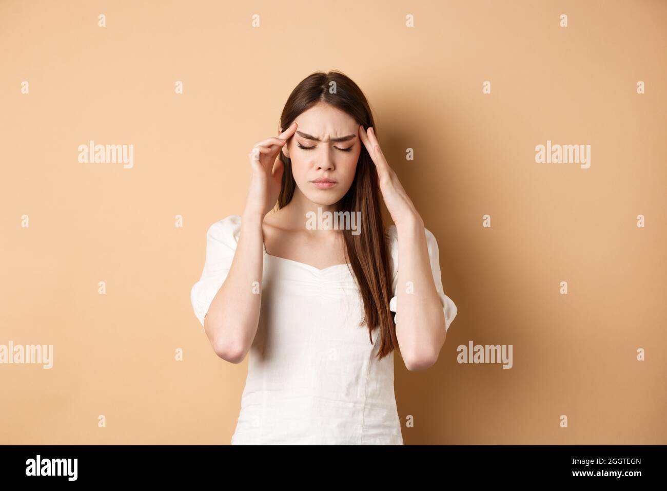 Young woman having headache, touching head temples with closed eyes and ...