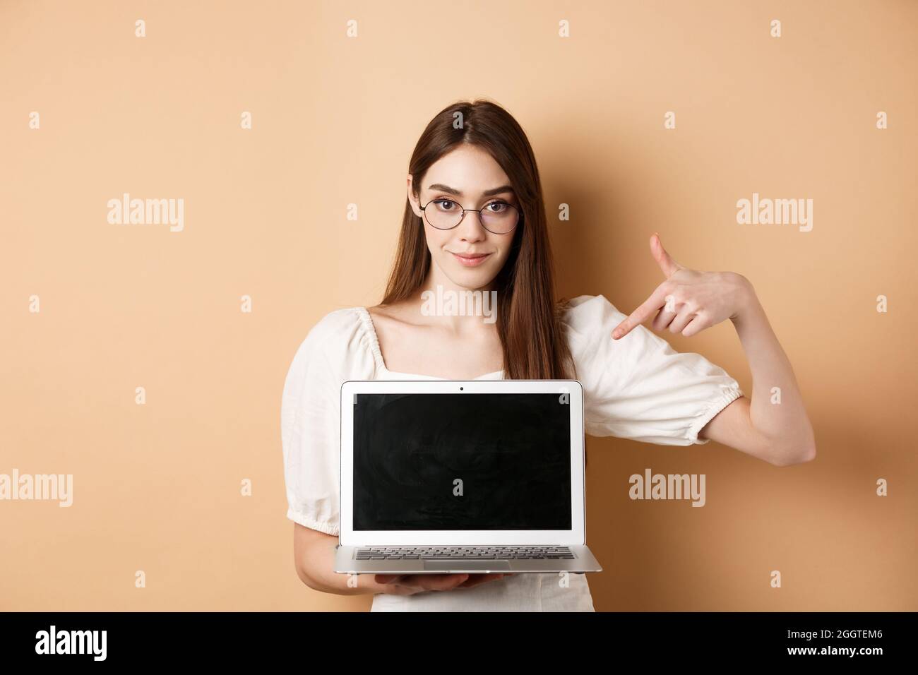 Confident young woman in glasses pointing at laptop screen, showing ...