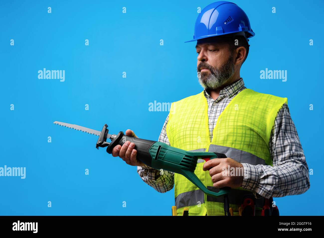 Handyman in uniform holding saw against blue background Stock Photo - Alamy