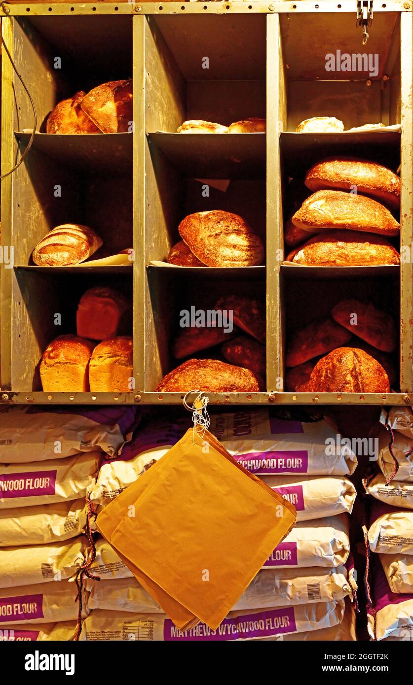 Freshly baked farmhouse crusty loaves on shelves and bags of bakers ...