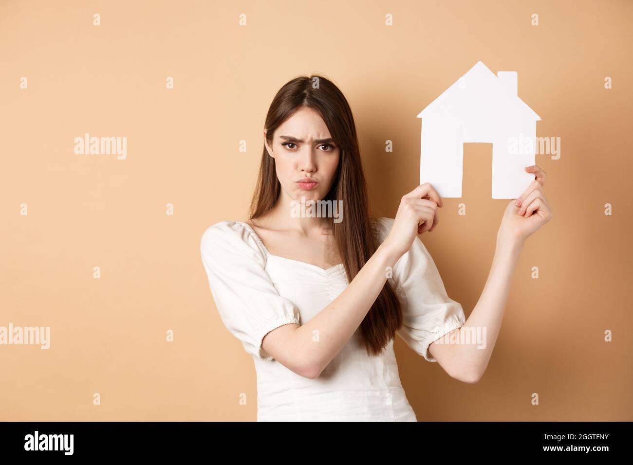 Real estate. Angry girl showing house cutout and frowning upset ...
