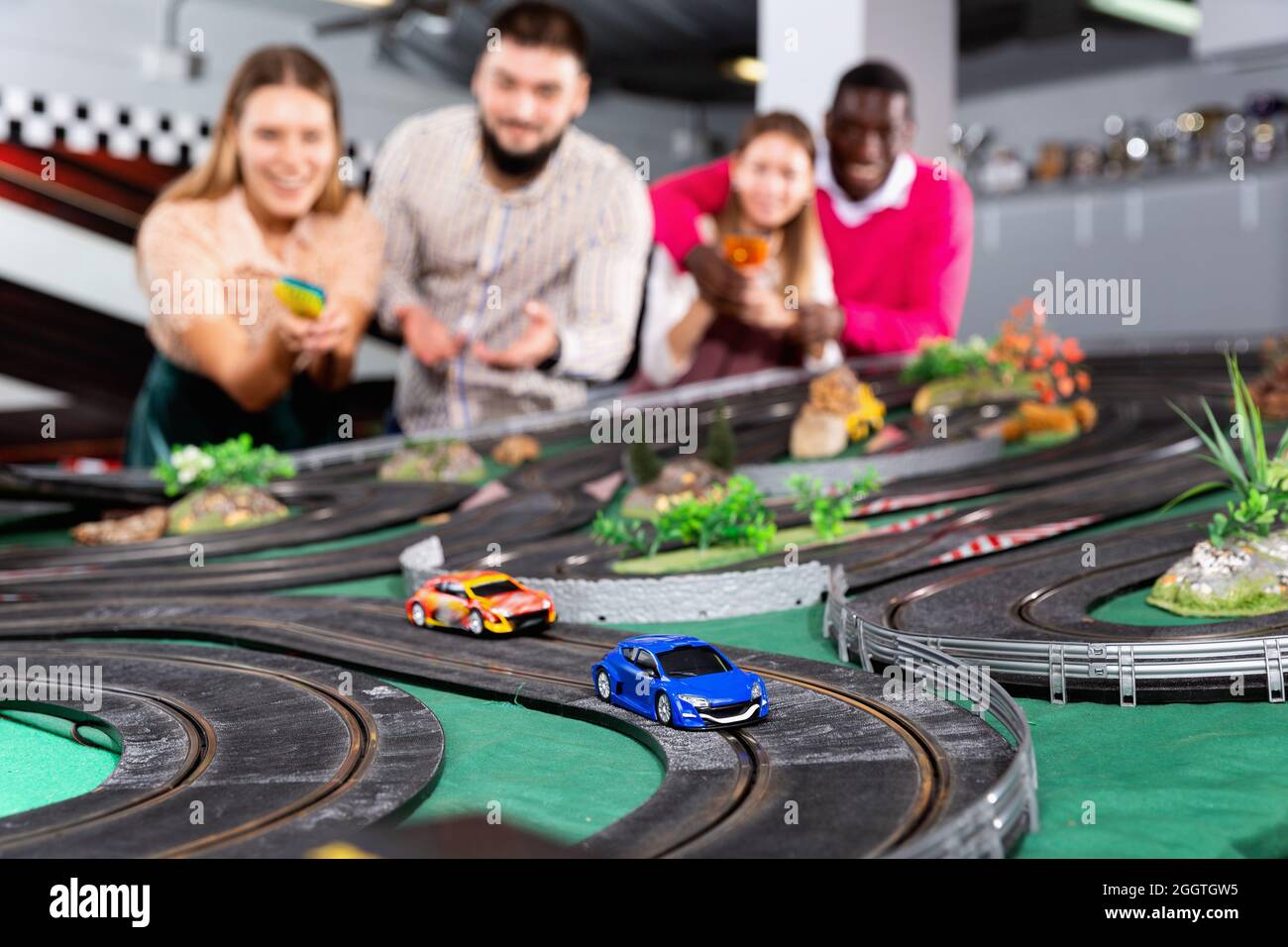 Toy remote control racing cars on the track and enthusiastic players ...