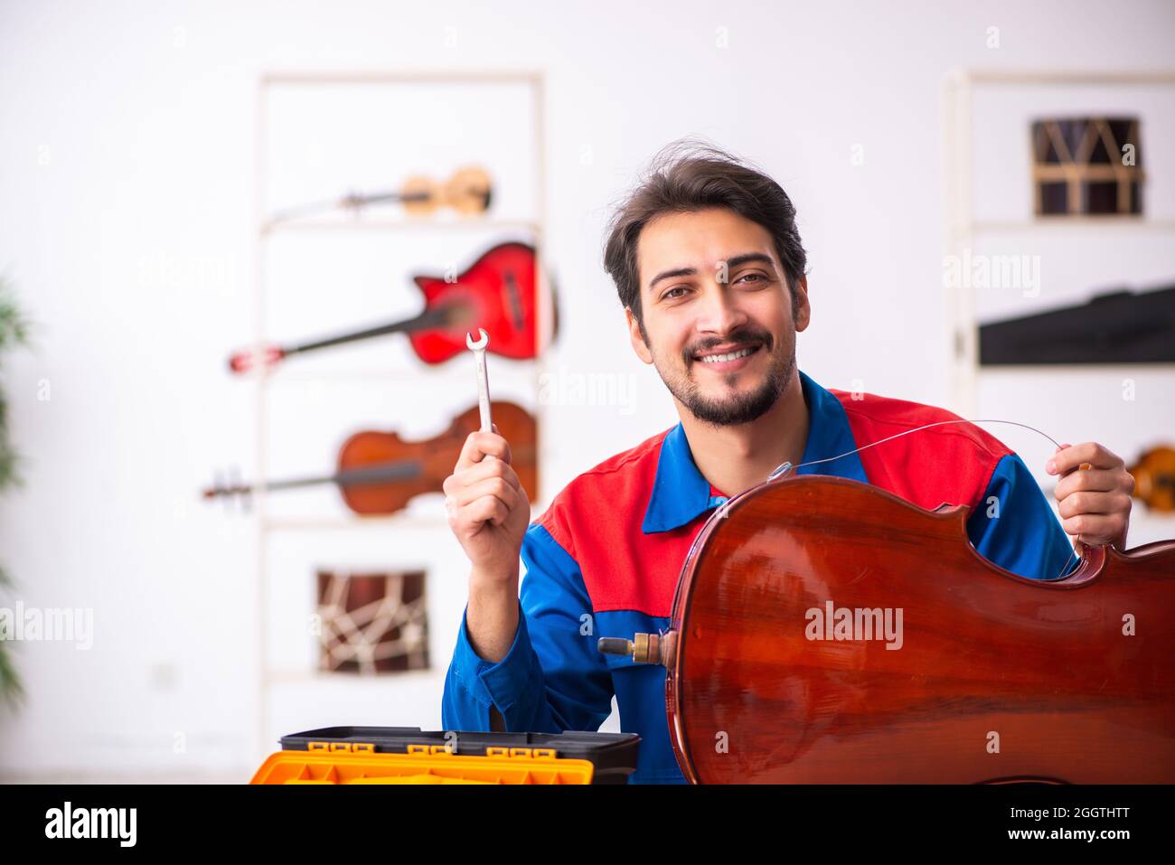 Young repairman repairing musical instruments at workplace Stock Photo ...