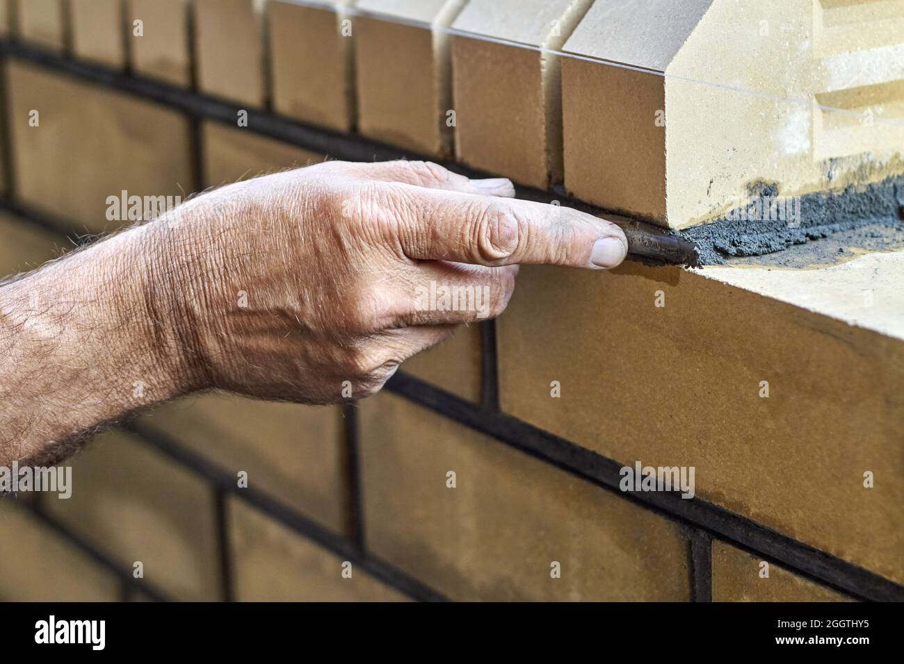 Bricklayer builds new fence from facing bricks. Alignment of inter ...