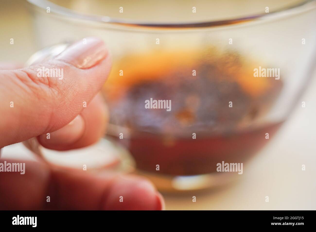 female fingers hold transparent cup with black tea in on the table ...
