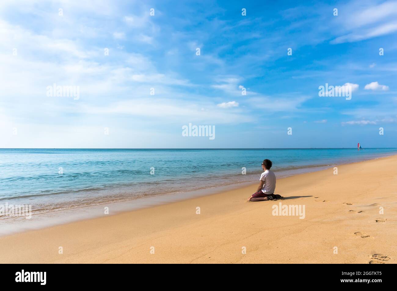 lonely sad man sitting on a beautiful deserted beach and looking into ...