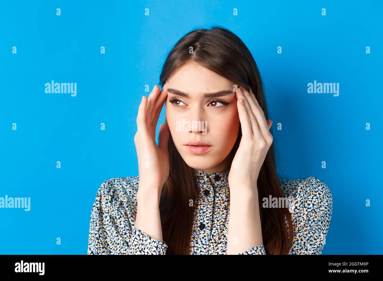 Close-up portrait of young woman feel sick, touching head temples and ...