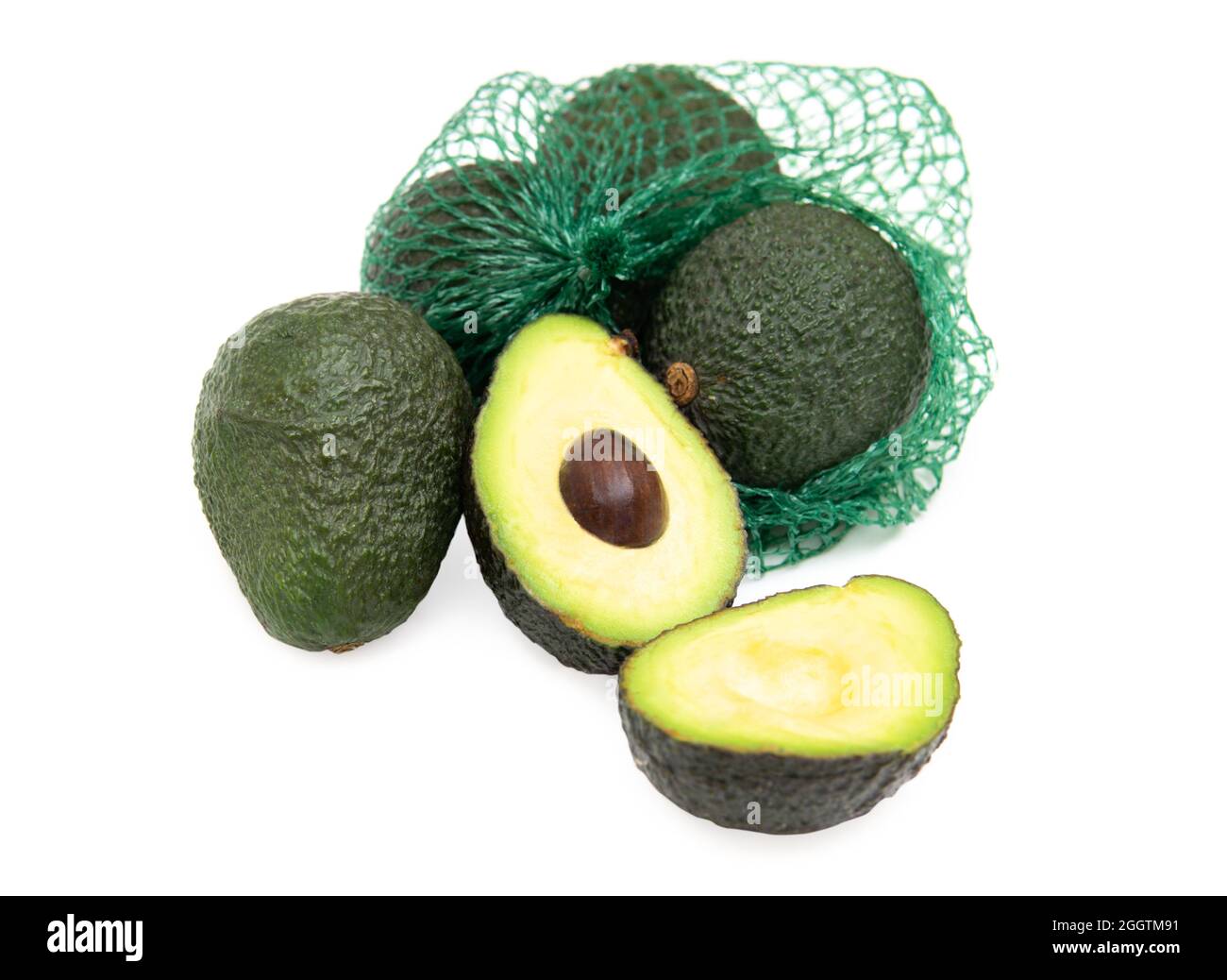 Group of fresh avocados in a green mesh bag isolated on white. One ...