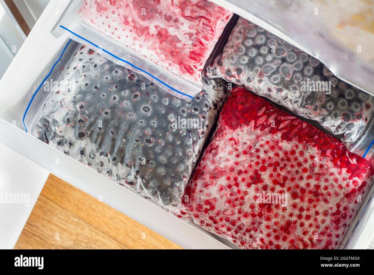 Frozen berries in transparent plastic bags in the freezer. Open deep ...