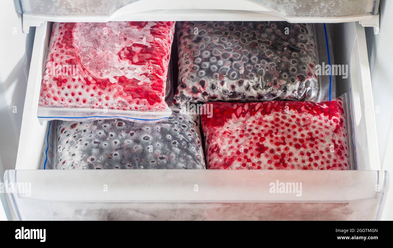 Frozen berries in transparent plastic bags in the freezer. Open deep ...