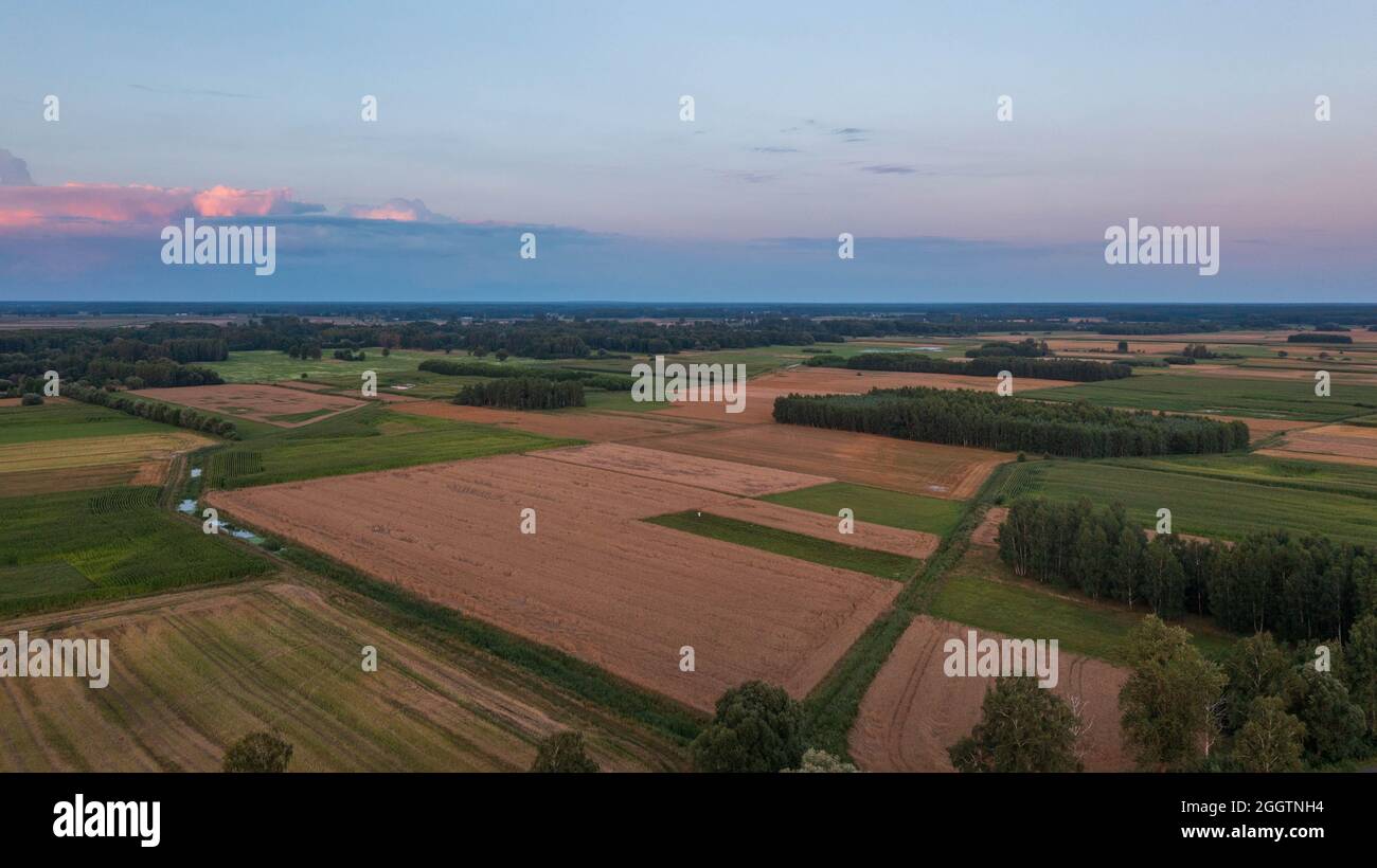 Sunset aerial landscape of filds and meadows with distant clouds in ...