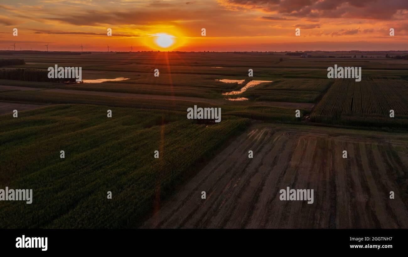 Colorful sunset over forest and fields aerial with sun and distant ...