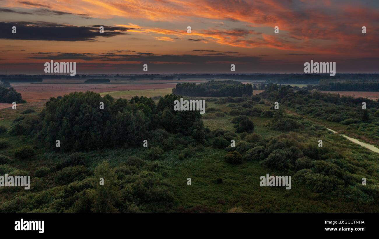 Colorful sunset over forest and fields aerial in sunset light ...