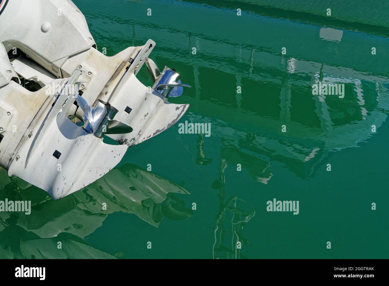 Twin outboard motors at the back of a boat. Shiny chrome propellers ...
