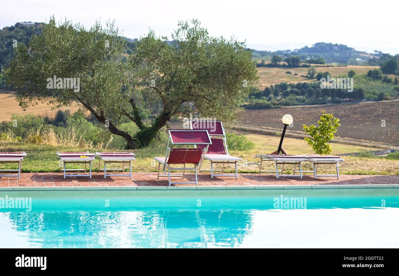 Red sunbeds by the pool in the Italian countryside (Tuscany, Italy ...