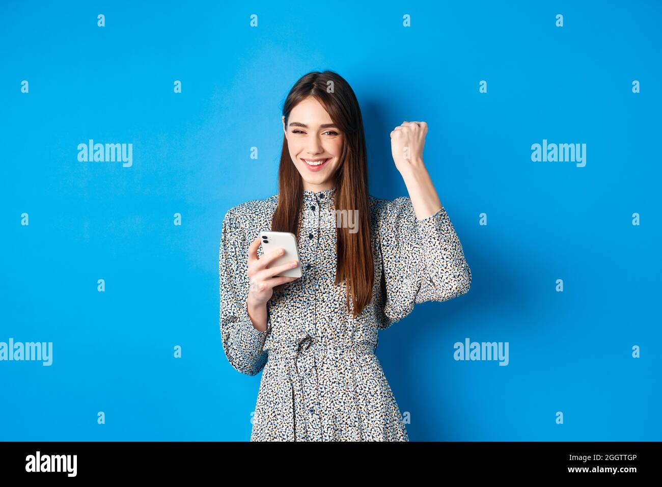 Happy pretty girl winning on mobile phone, smiling and chanting ...