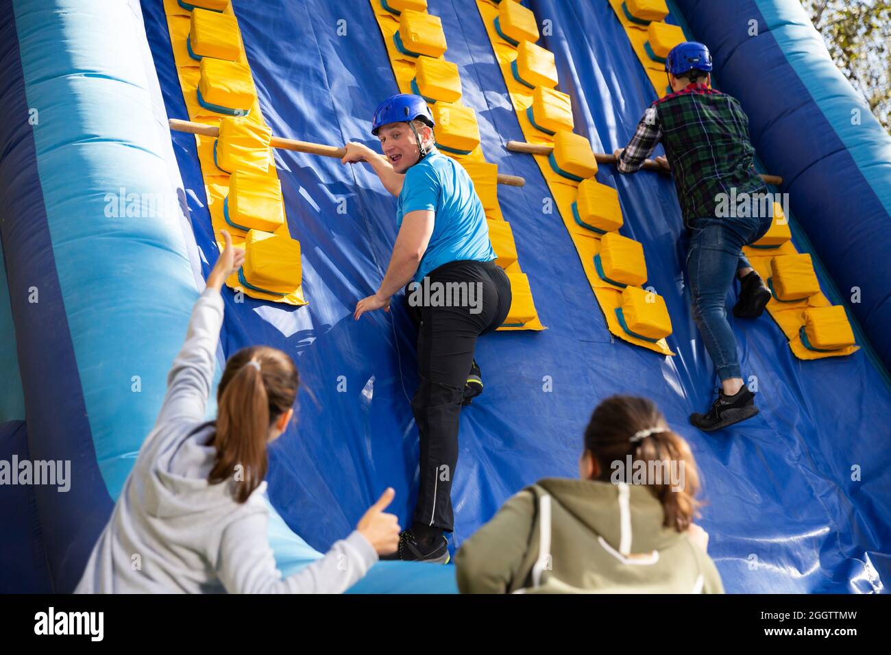 Friends climbing on inflatable slide in amusement park Stock Photo - Alamy