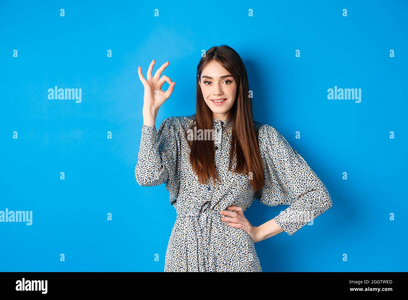 Confident young woman in dress showing okay sign and smiling, no ...