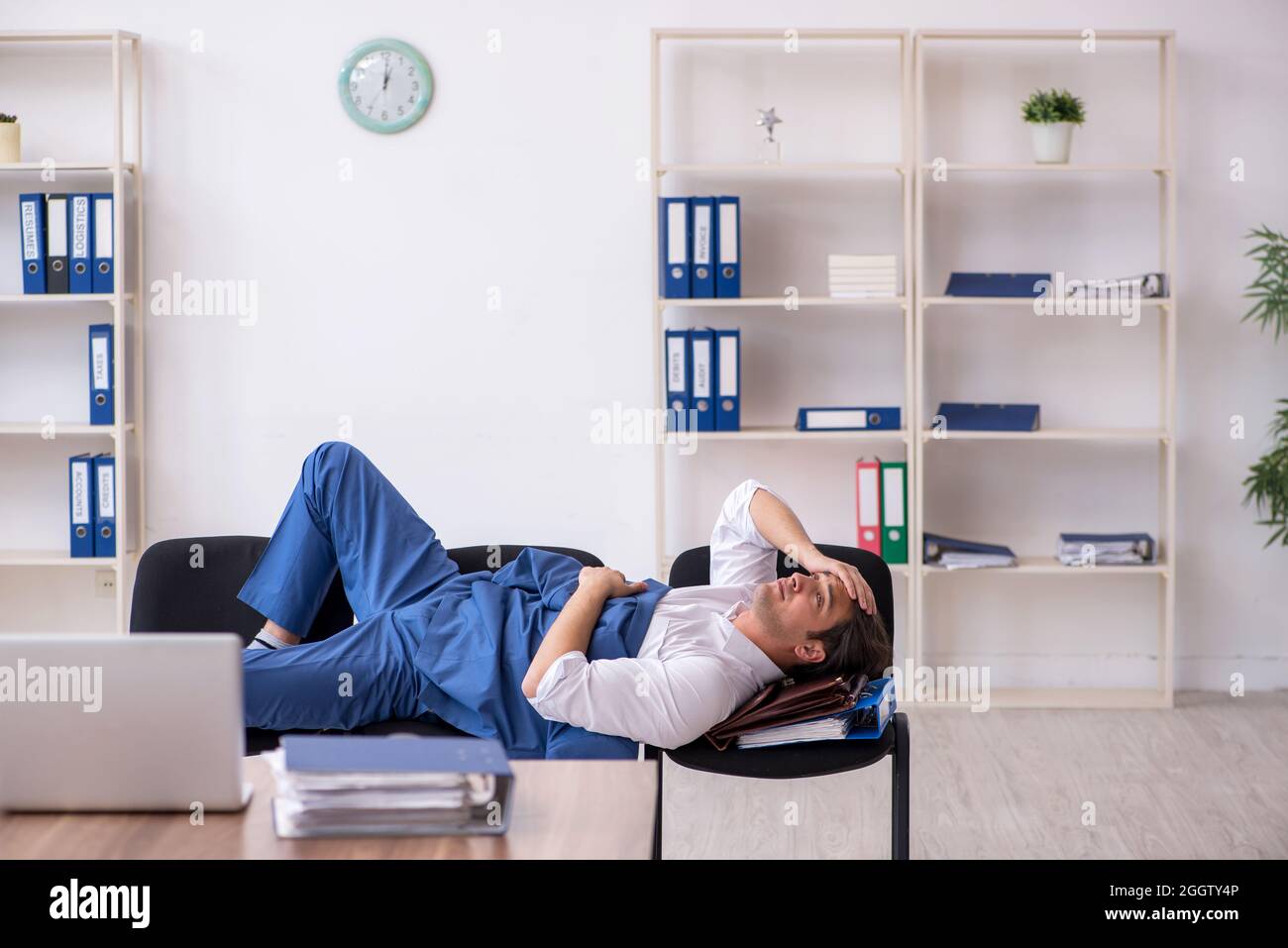 Young employee sleeping in the office on chairs Stock Photo - Alamy
