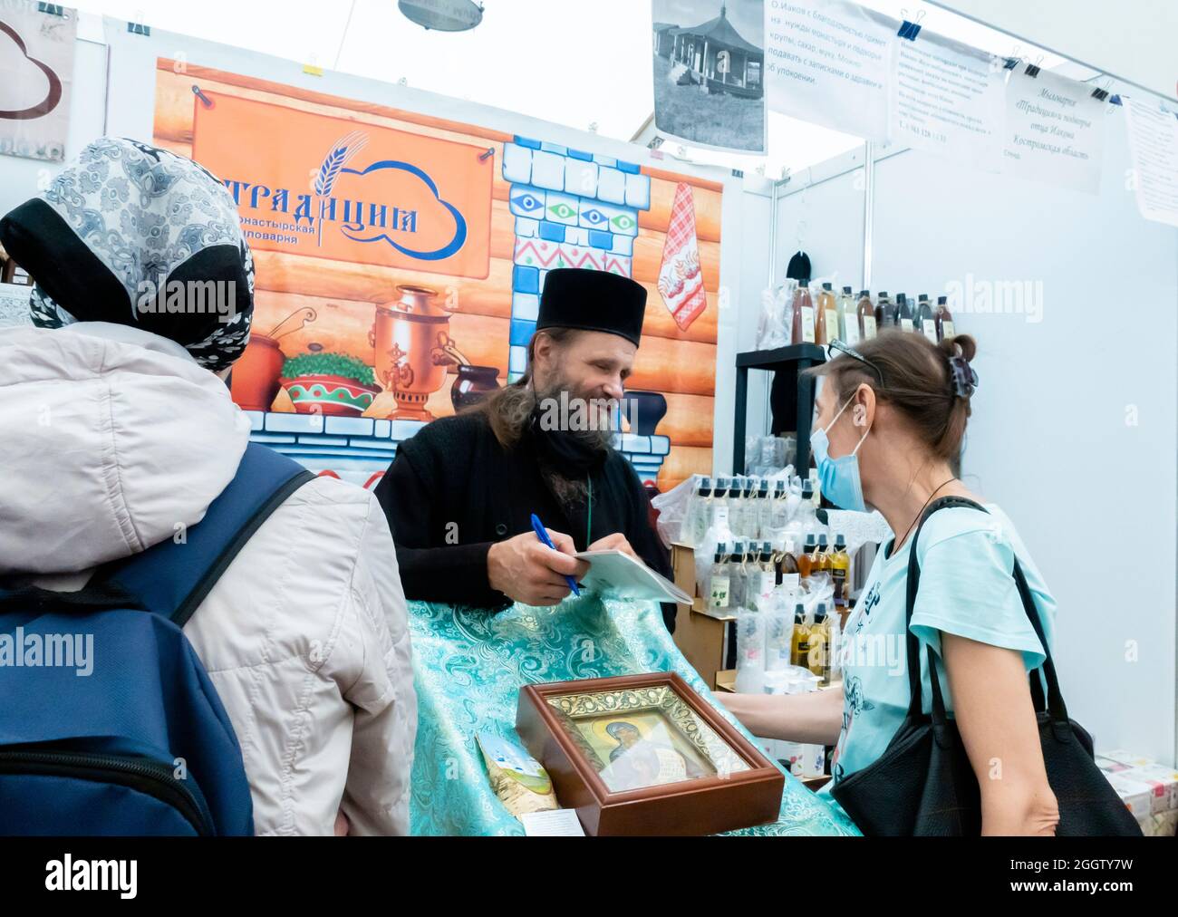 A male priest in uniform of Orthodox temple attending to customer at ...