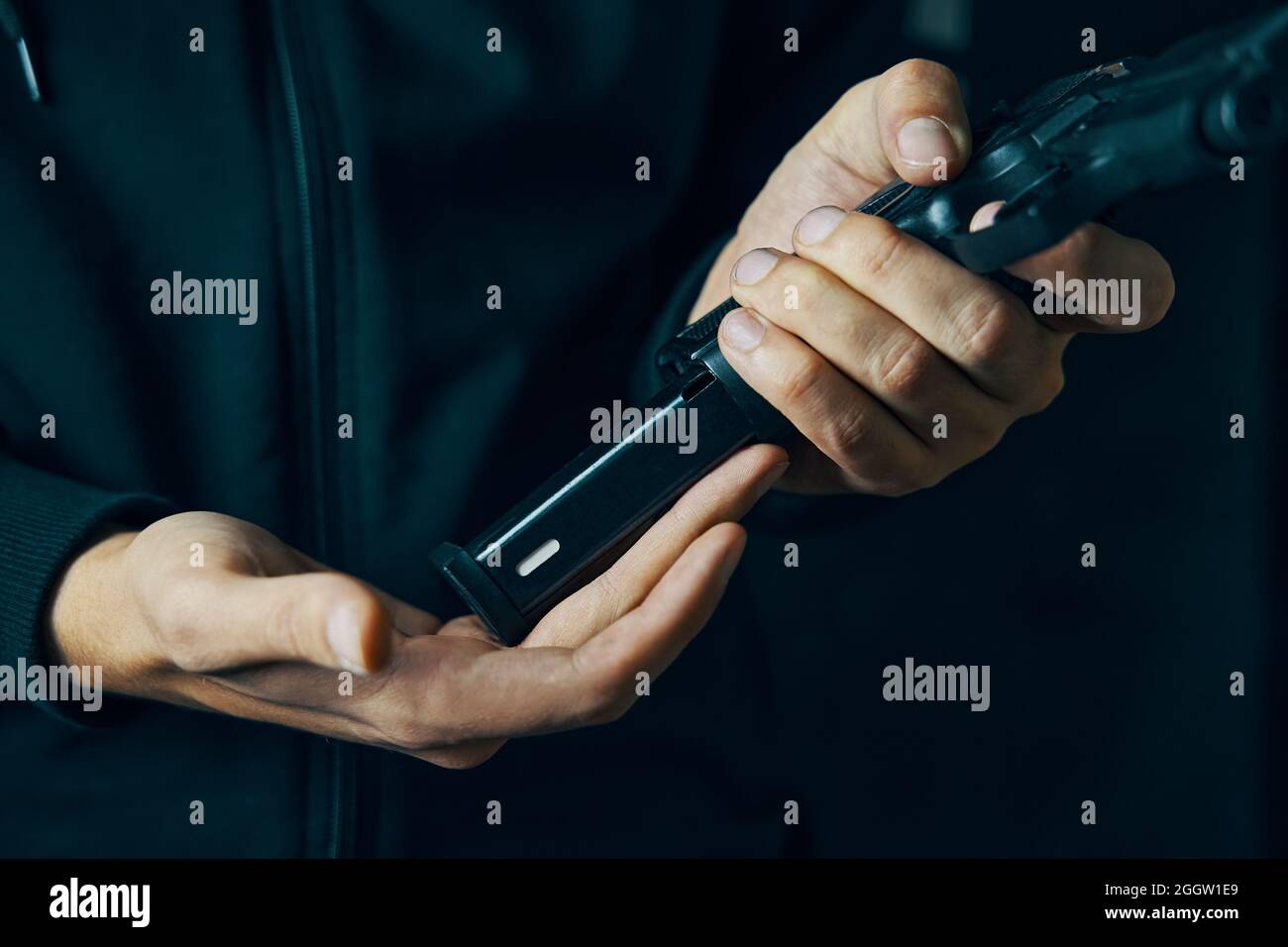 Reloading pistol close-up. Man inserts drum of cartridges into gun ...