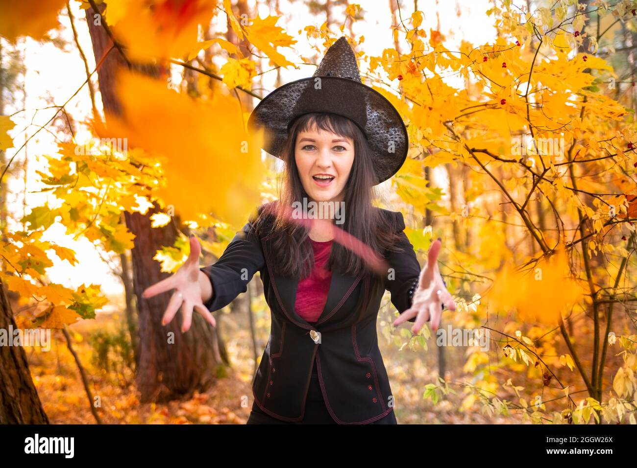 the witch making magic. woman in a witch costume laughs and throws ...